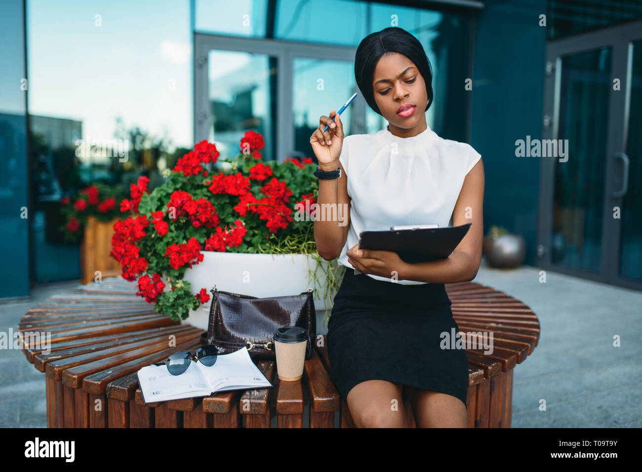 Business woman with notepad resting on the bench during the break in ...