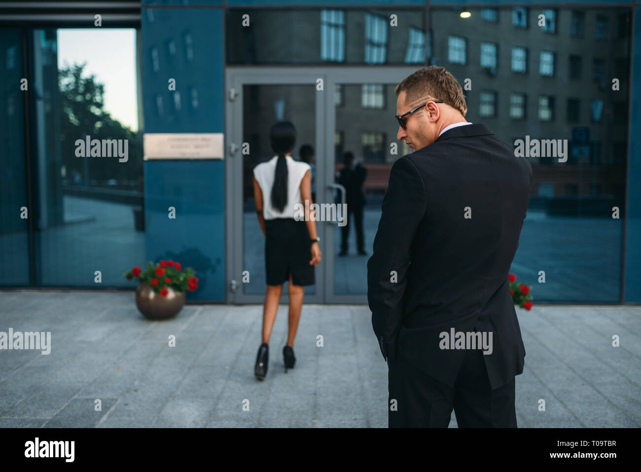 Personal guard in sunglasses and security earpiece, back view, black ...