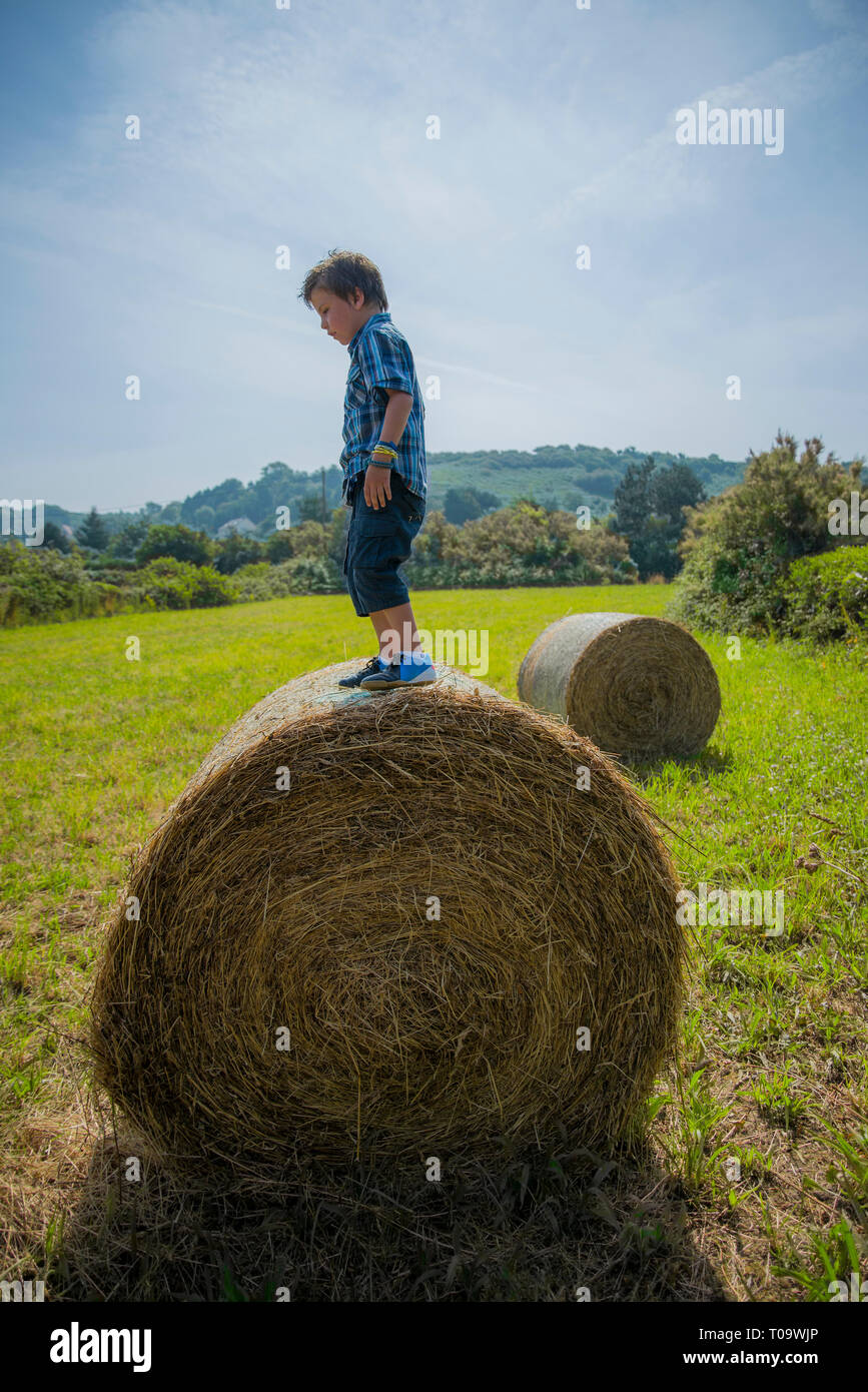 kid standing on a round hay bale,looks like he's balancing on it Stock ...