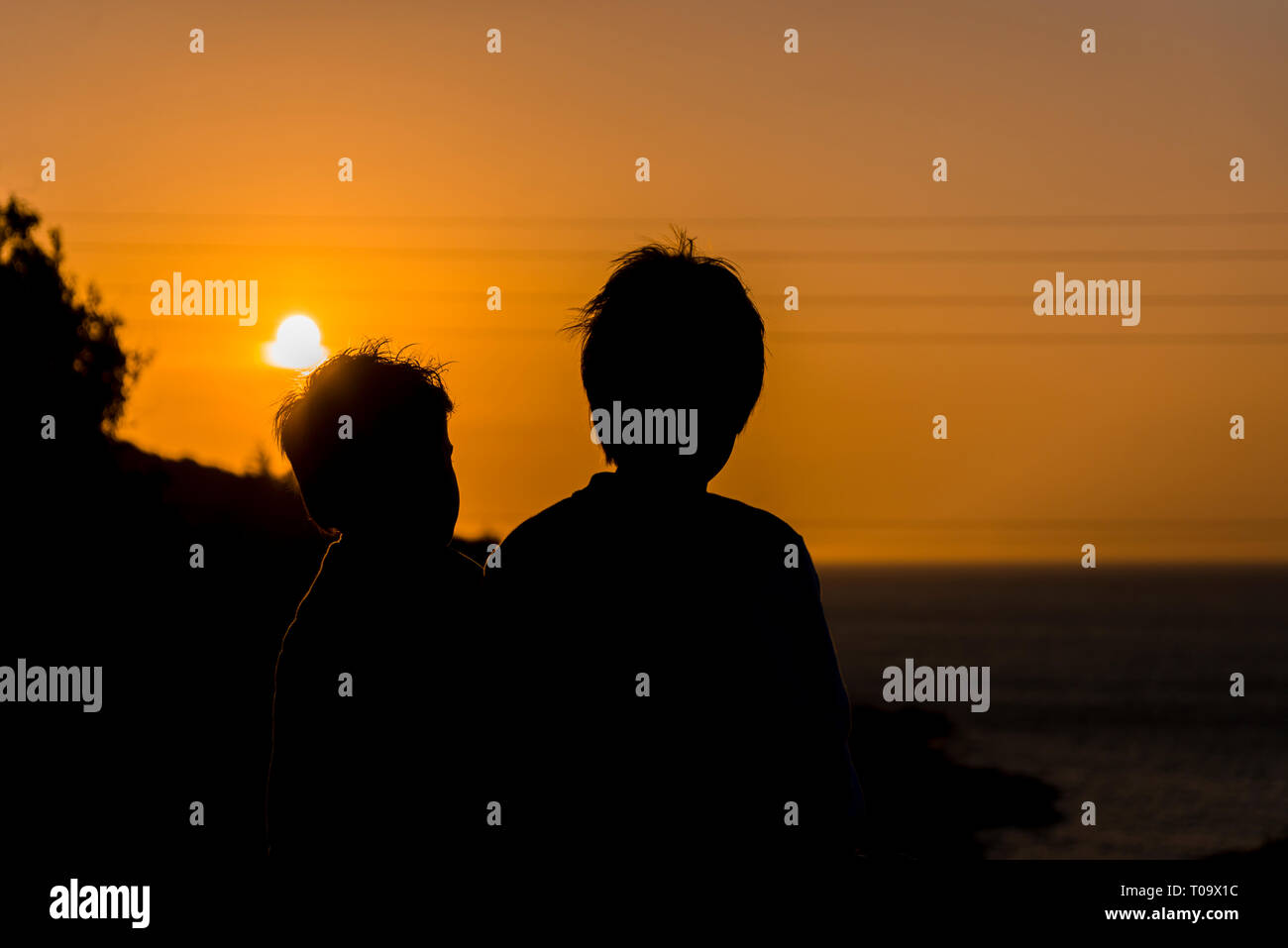 silhouettes of two boys looking at sunset Stock Photo - Alamy