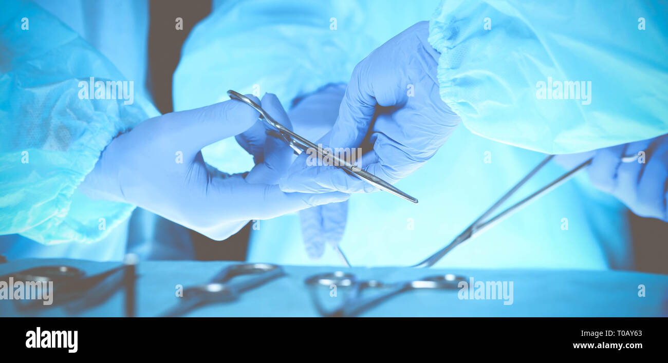 Surgeons hands holding surgical scissors and passing surgical equipment ...
