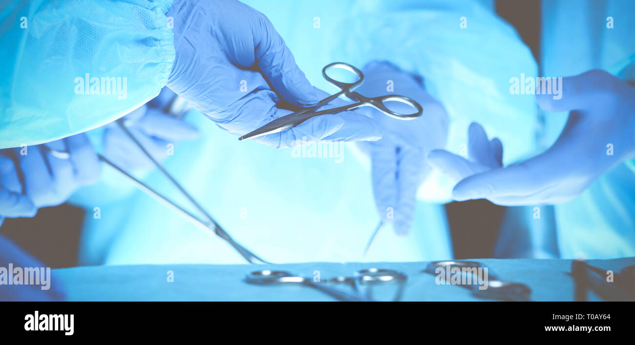 Surgeons hands holding surgical scissors and passing surgical equipment ...