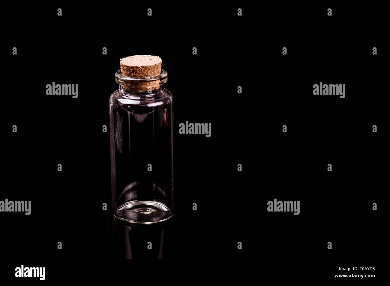 Single empty tiny glass bottle with a cork isolated over the black ...