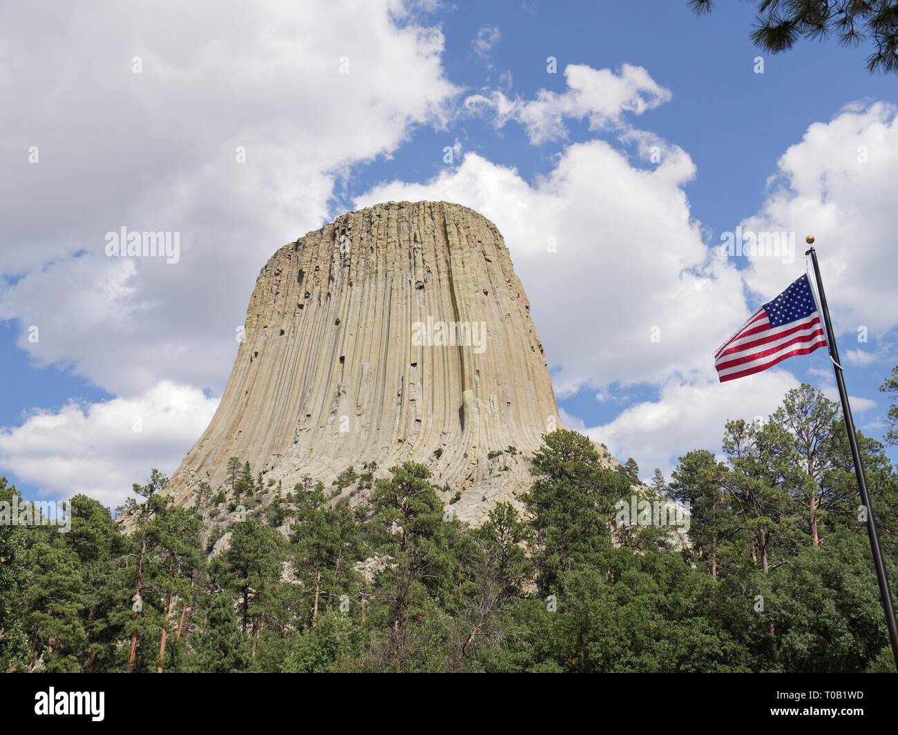 Medium wide shot of the Devils Tower, with a United States flag flying ...