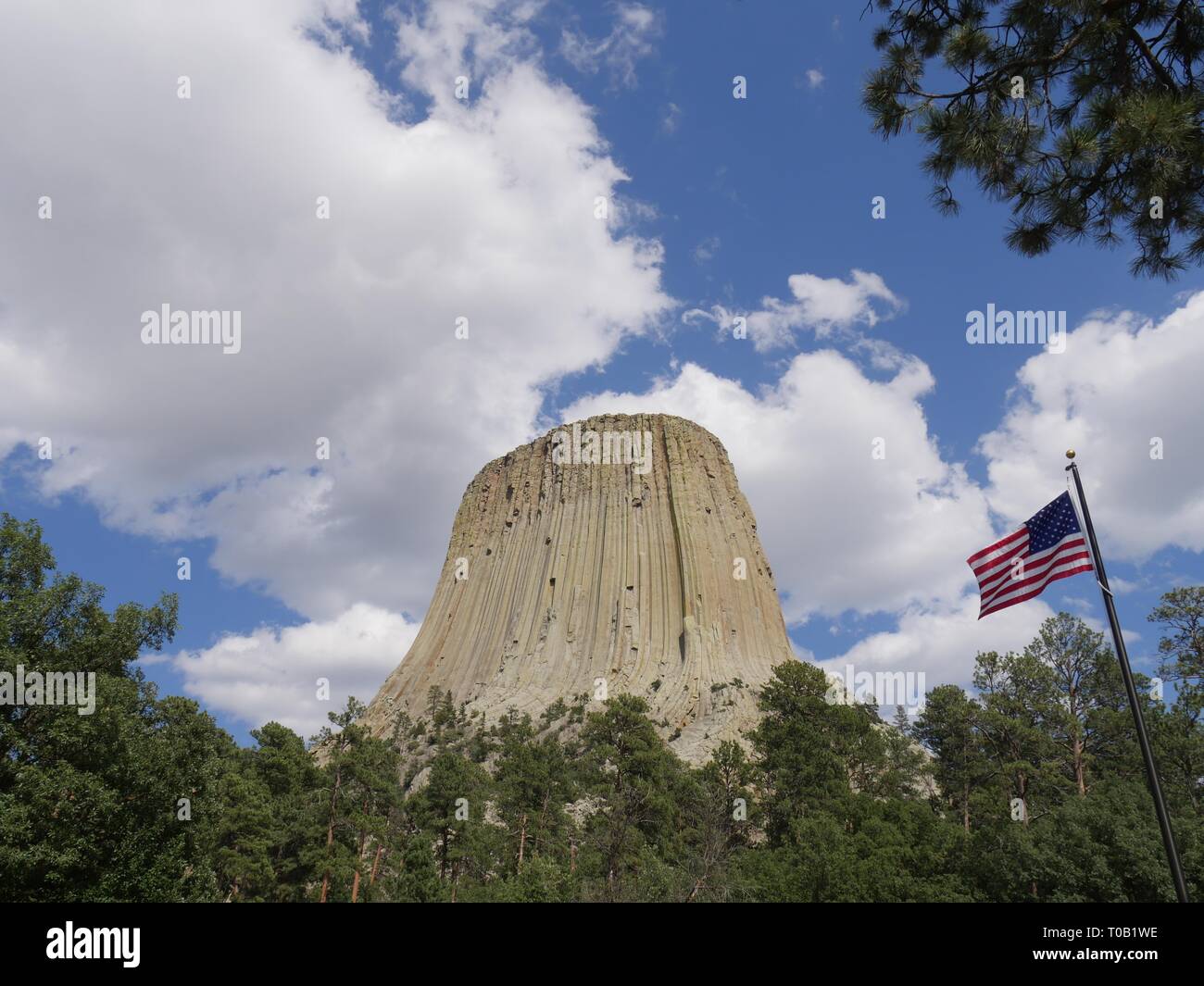 Wide shot of the Devils Tower, with a United States flag flying nearby ...