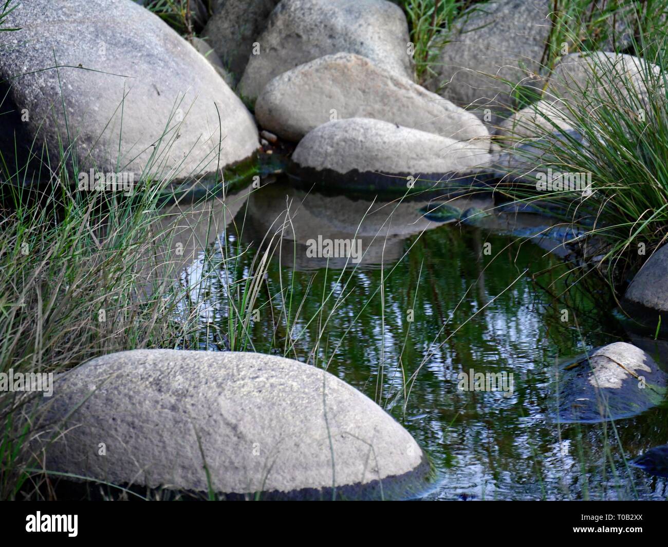 Small pool of water surrounded by rocks in the river Stock Photo - Alamy