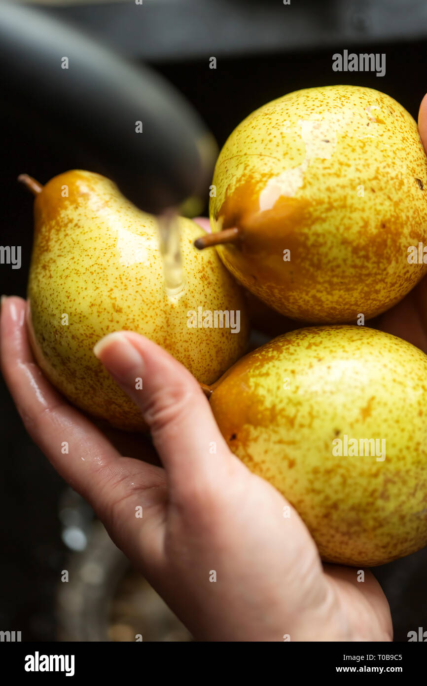 Girl washing pears under water in sink Stock Photo - Alamy