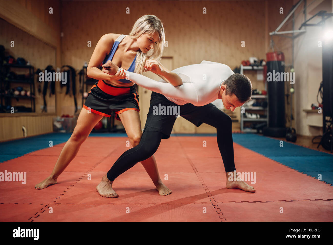 Woman makes elbow kick, self-defense workout with male personal trainer ...