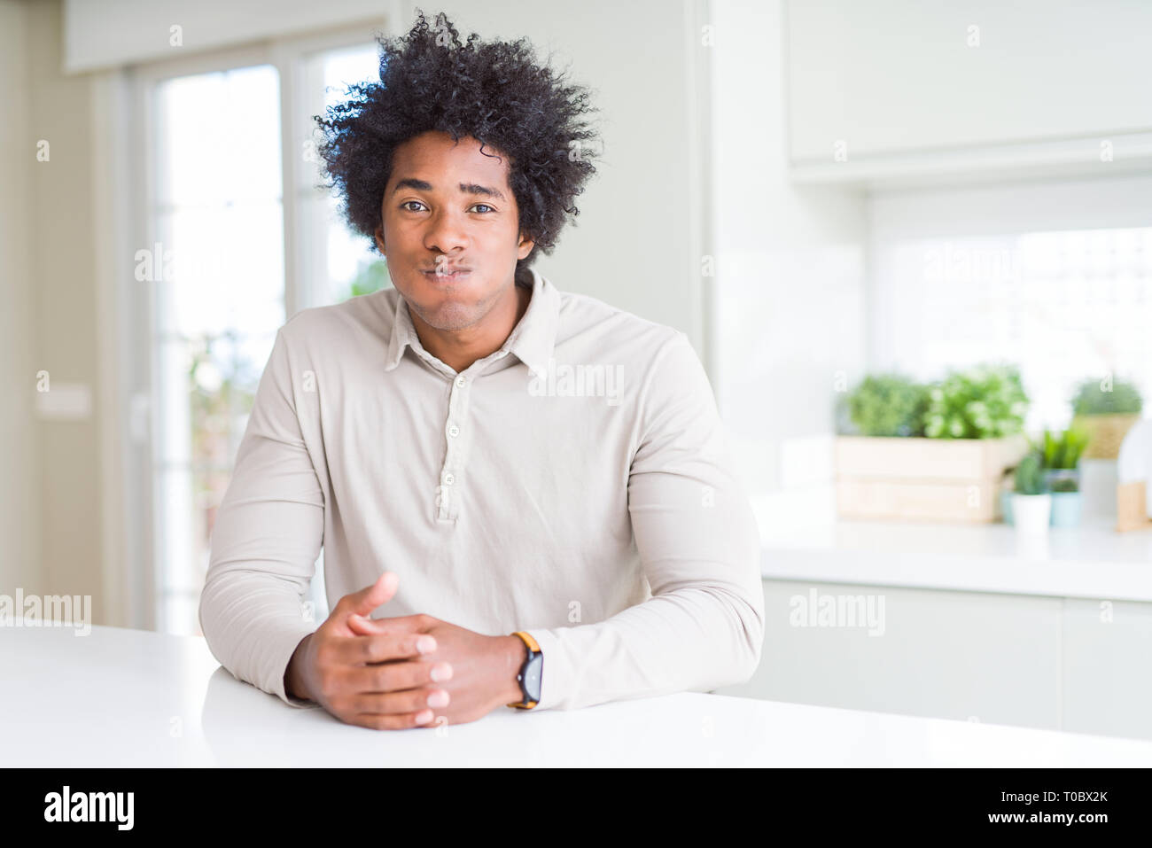 African American man at home puffing cheeks with funny face. Mouth ...