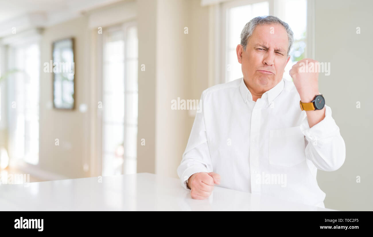Handsome senior man at home angry and mad raising fist frustrated and ...
