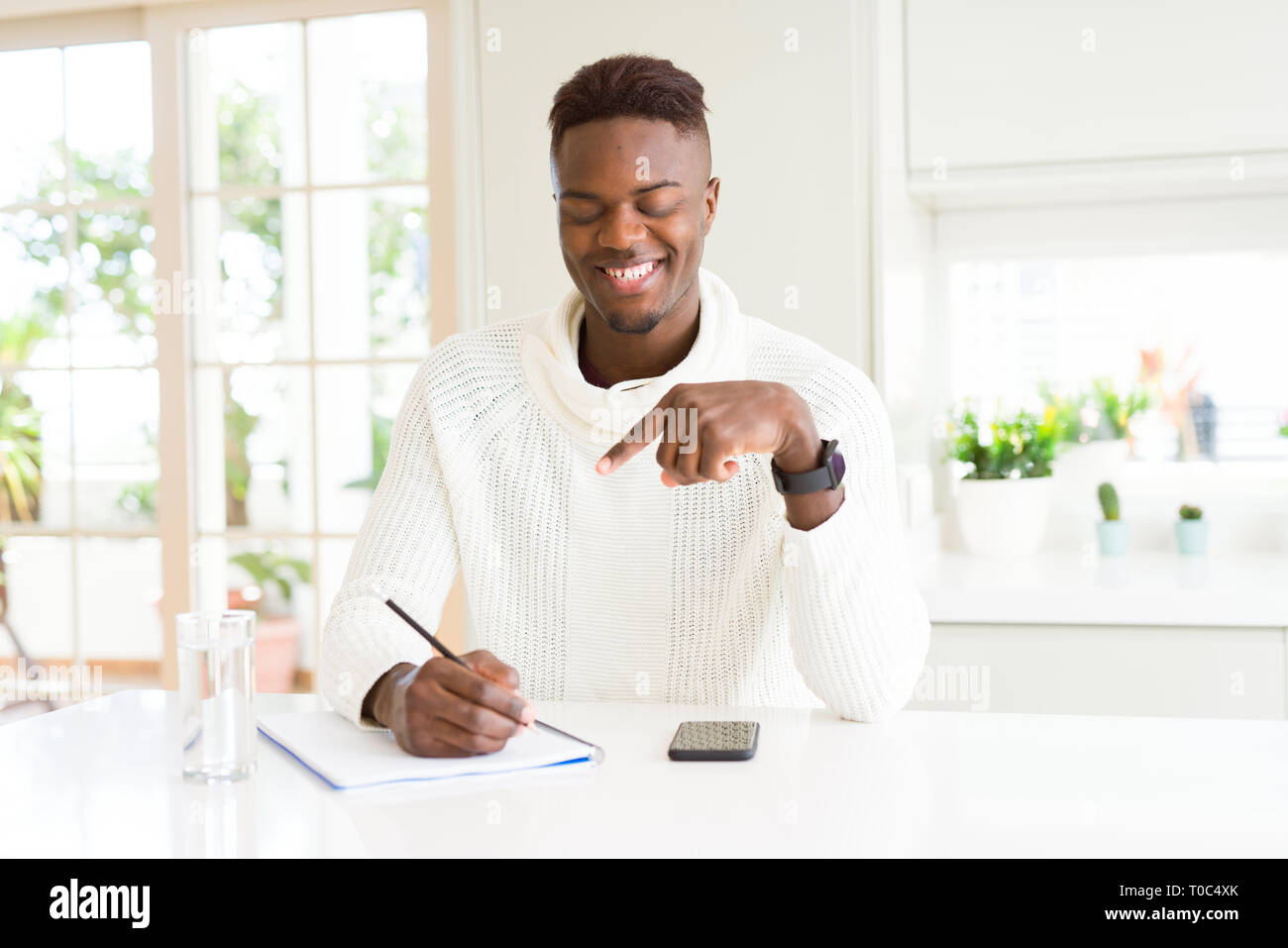 African american student man writing on a paper using a pencil very ...