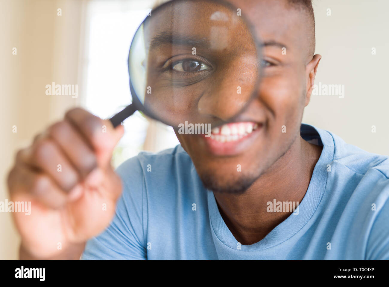 Young african man looking through magnifying glass Stock Photo - Alamy