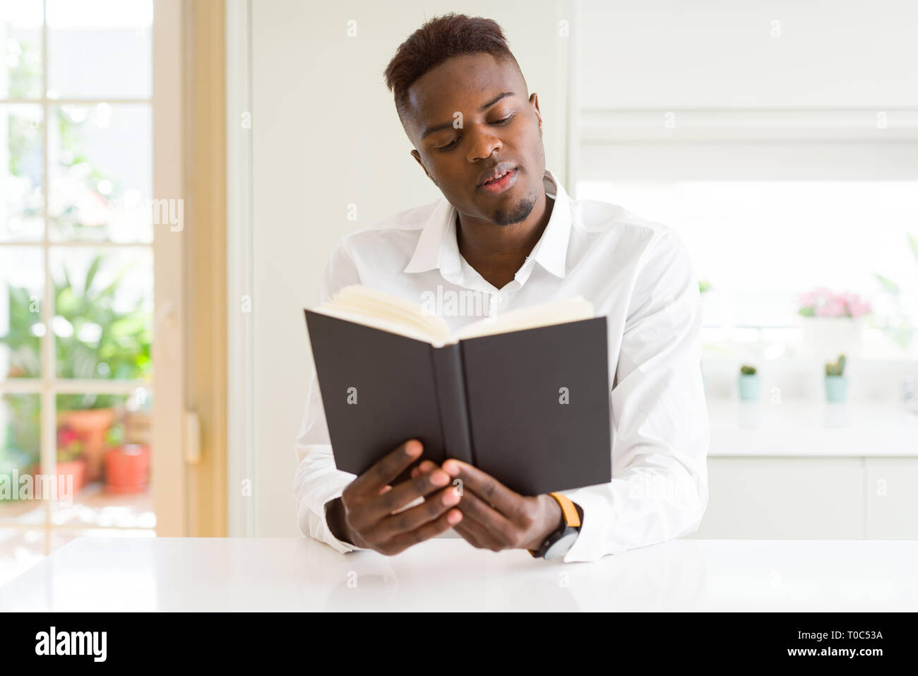Young african man reading a book, studying for univeristy Stock Photo ...