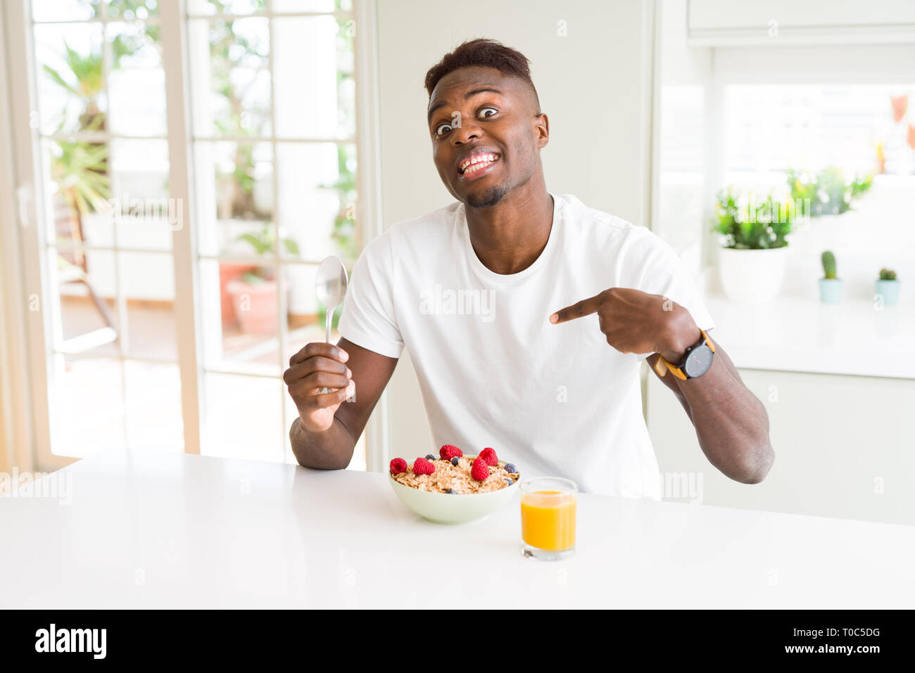 Young african american man eating healthy breakfast in the morning with ...