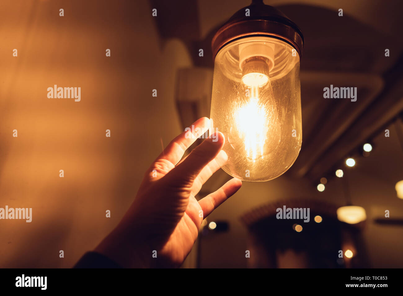 Hand reaching for a vintage light bulb Stock Photo - Alamy