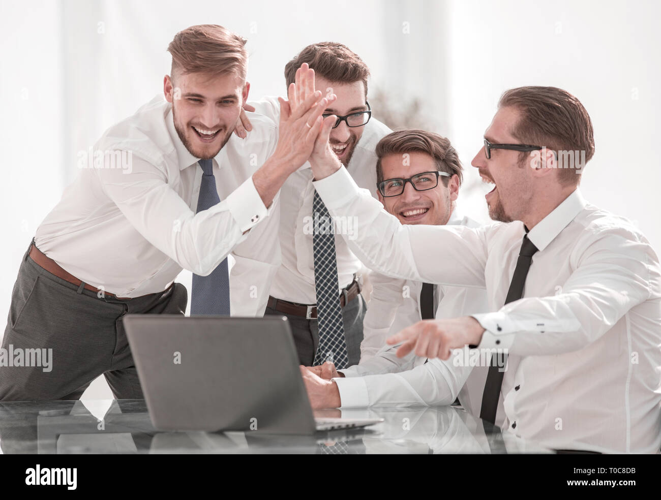 Happy excited team looking at the laptop screen Stock Photo - Alamy