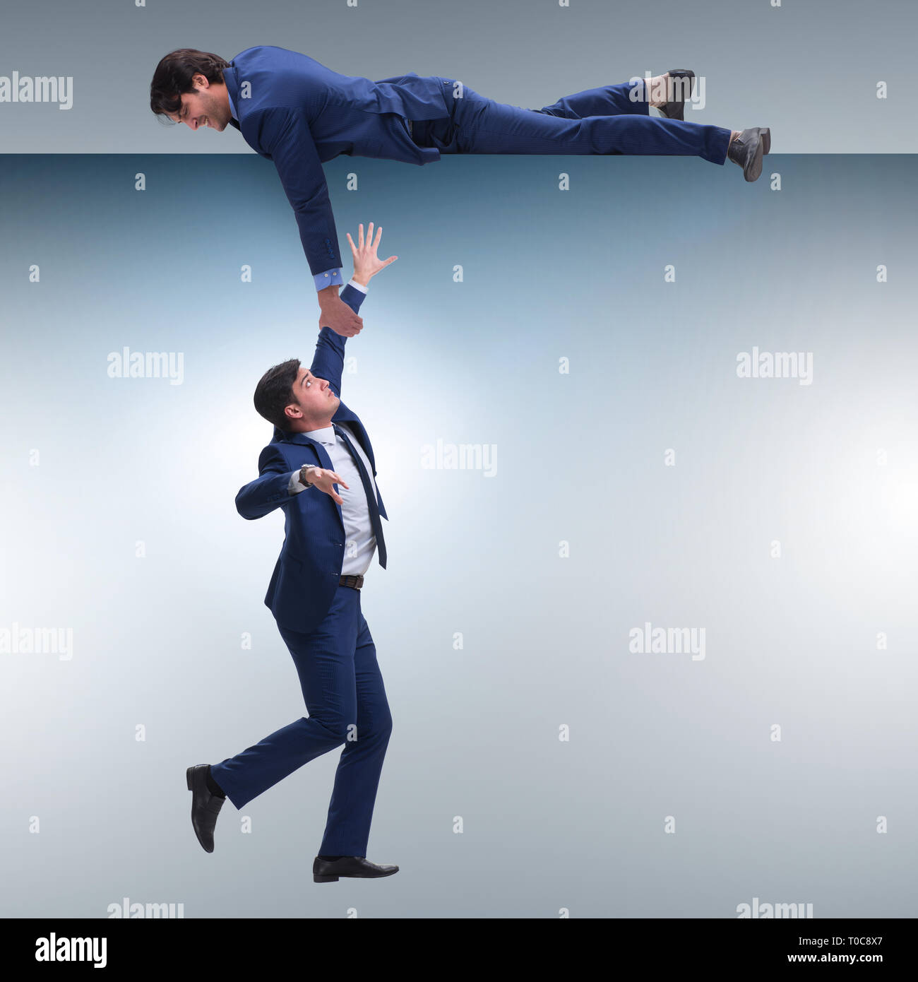 Businessman offering helping hand to falling colleague Stock Photo - Alamy