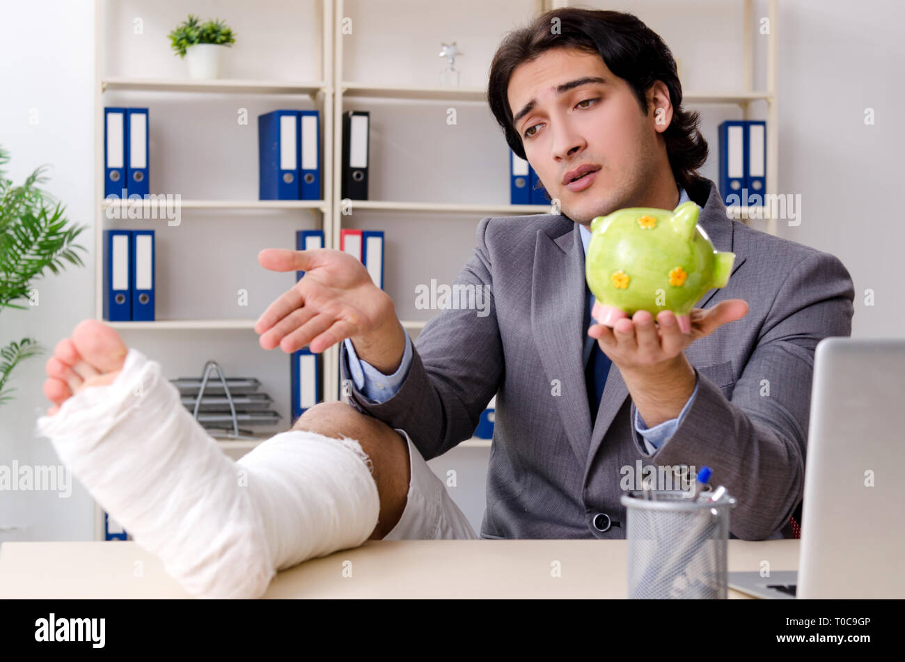 Leg injured employee working in the office Stock Photo - Alamy