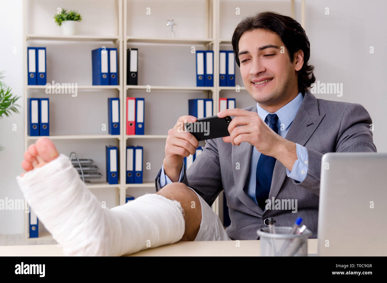 Leg injured employee working in the office Stock Photo - Alamy