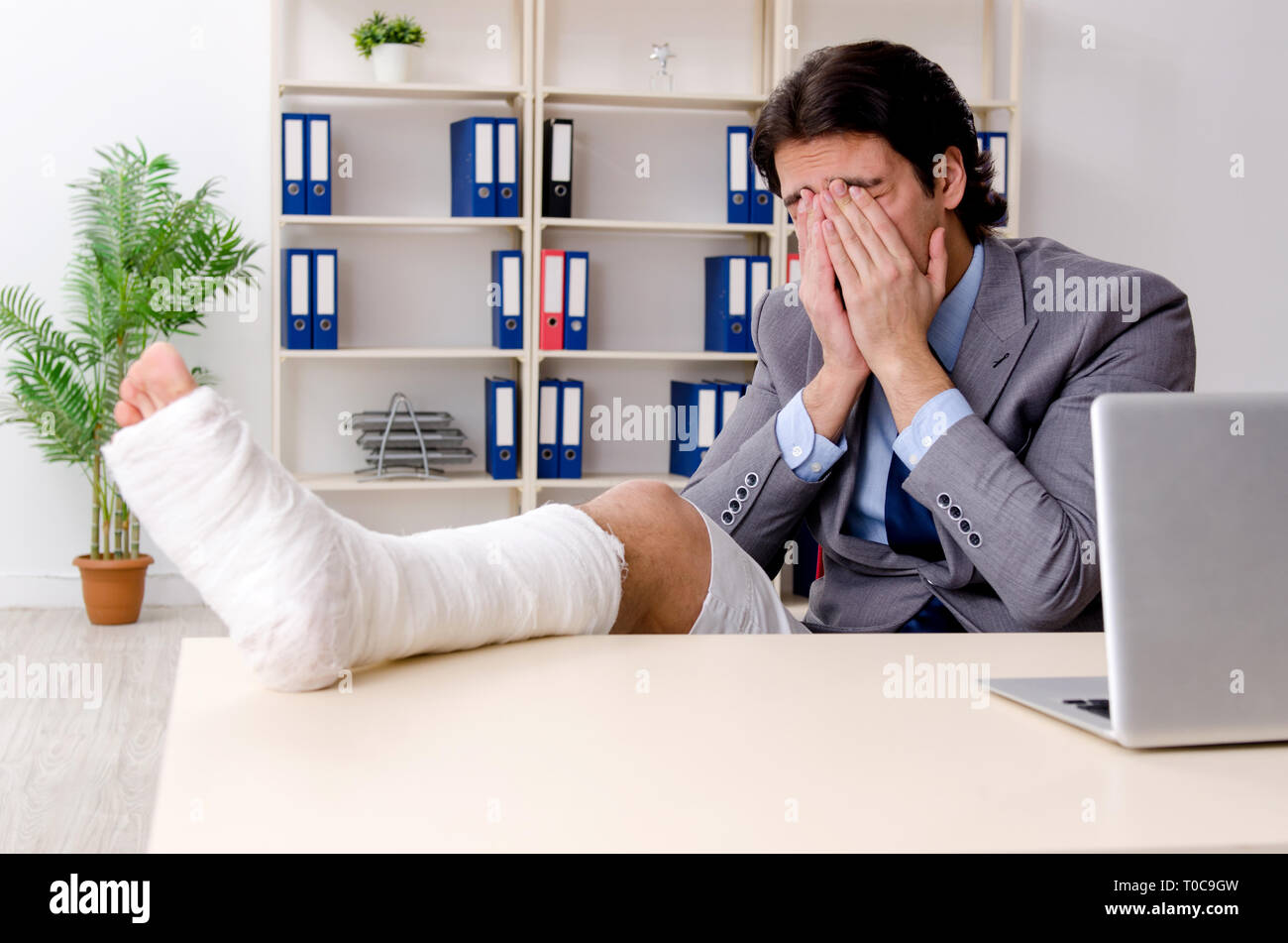 Leg injured employee working in the office Stock Photo - Alamy