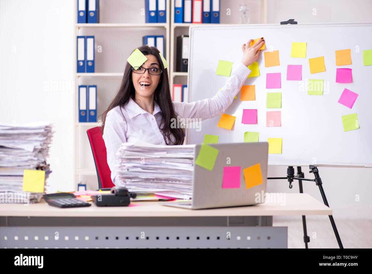 Young female employee in conflicting priorities concept Stock Photo - Alamy