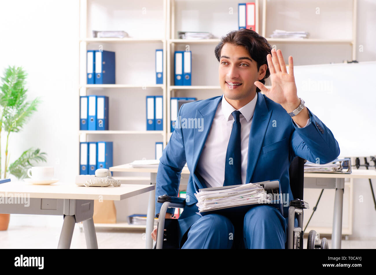 Male employee in wheelchair working at the office Stock Photo - Alamy