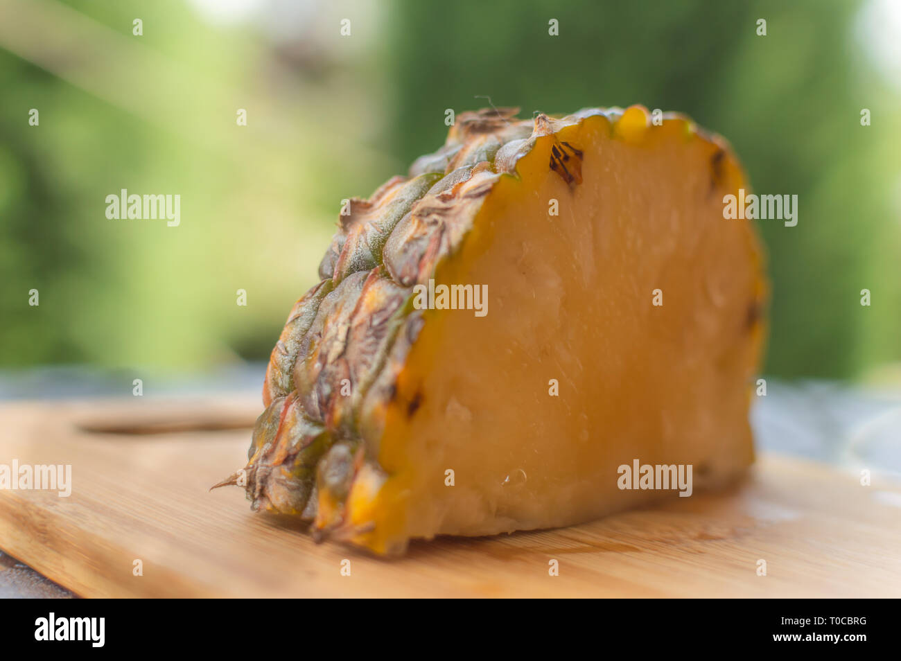 A quarter slice of a ripe pineapple kept vertically on a table outdoors ...