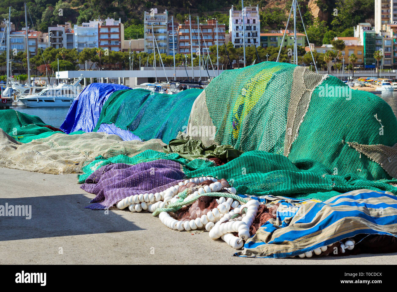 Empty green fishing net with floats lying on embankment of marine port ...