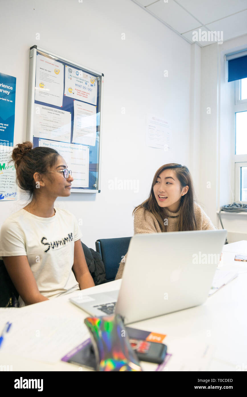 pupils and students in a classroom at a college / university, being taught a lesson while in ...