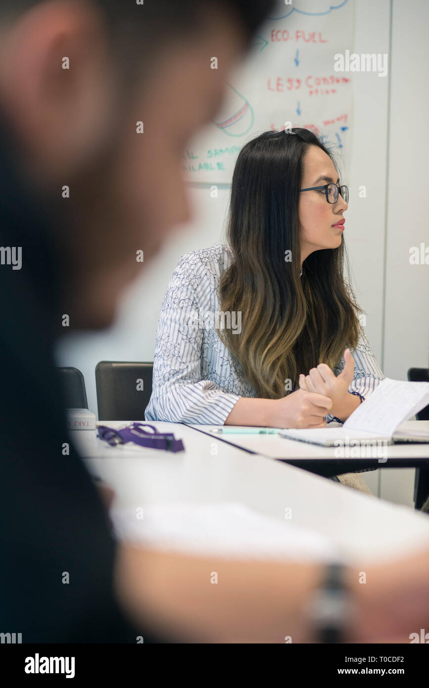 pupils and students in a classroom at a college / university, being taught a lesson while in ...