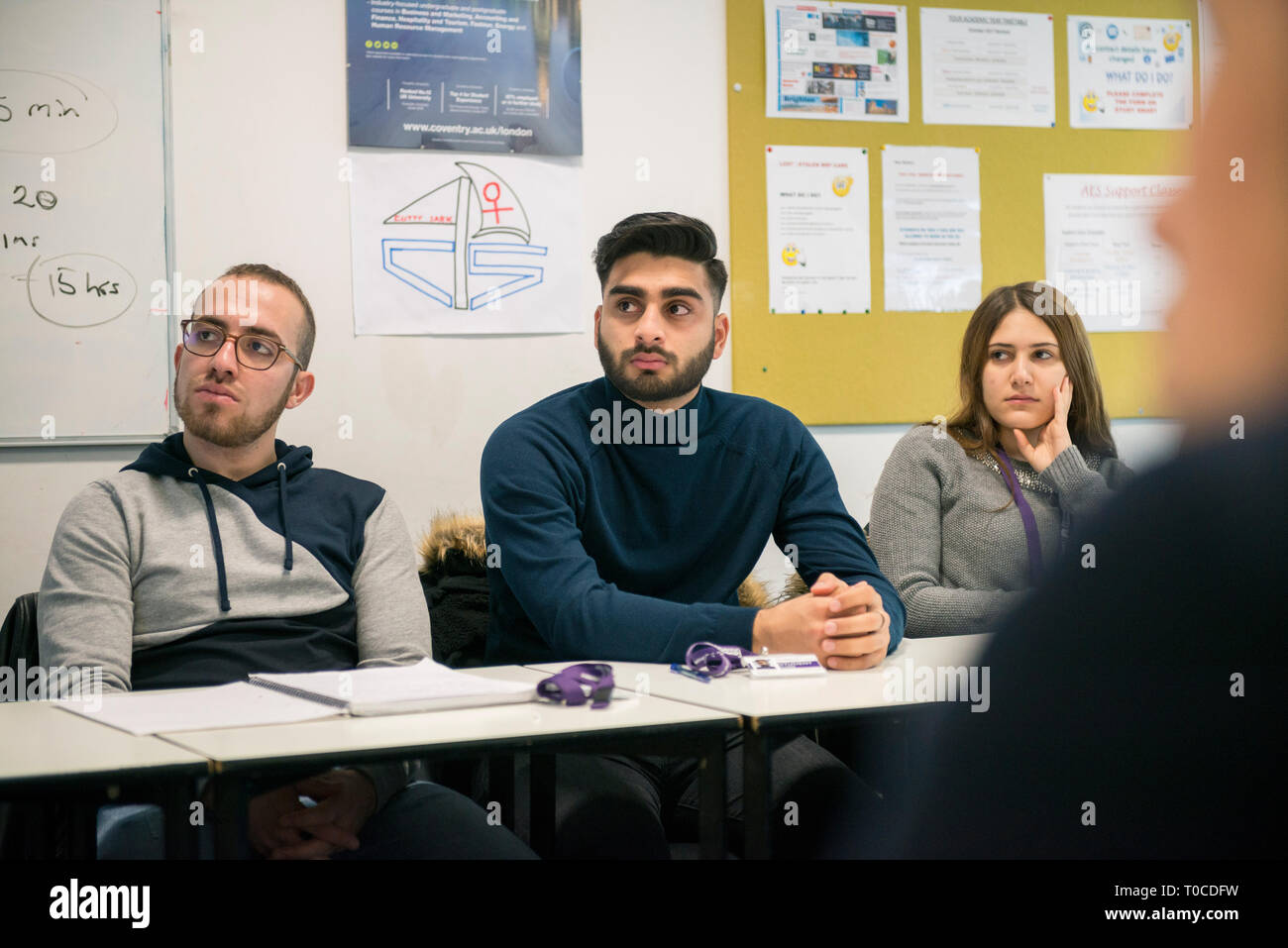 pupils and students in a classroom at a college / university, being taught a lesson while in ...