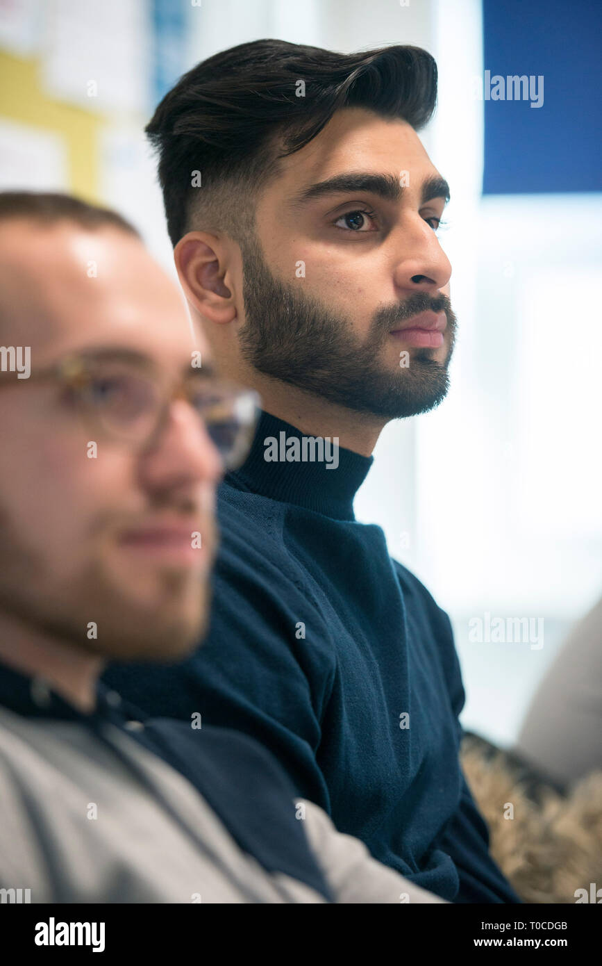 pupils and students in a classroom at a college / university, being taught a lesson while in ...