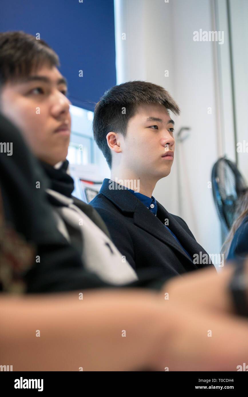 pupils and students in a classroom at a college / university, being taught a lesson while in ...