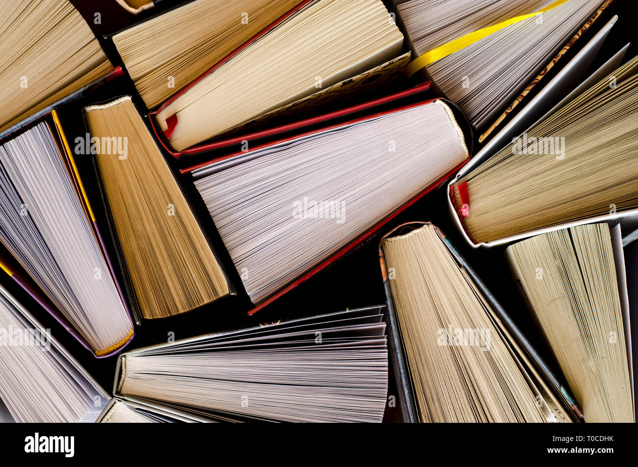 Lots of colourful thick open books stand on a dark background. ready to ...