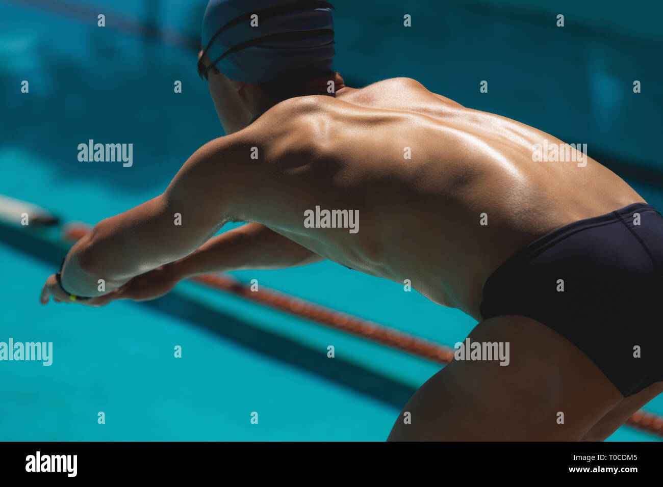 Young male swimmer in starting position at swimming pool Stock Photo ...