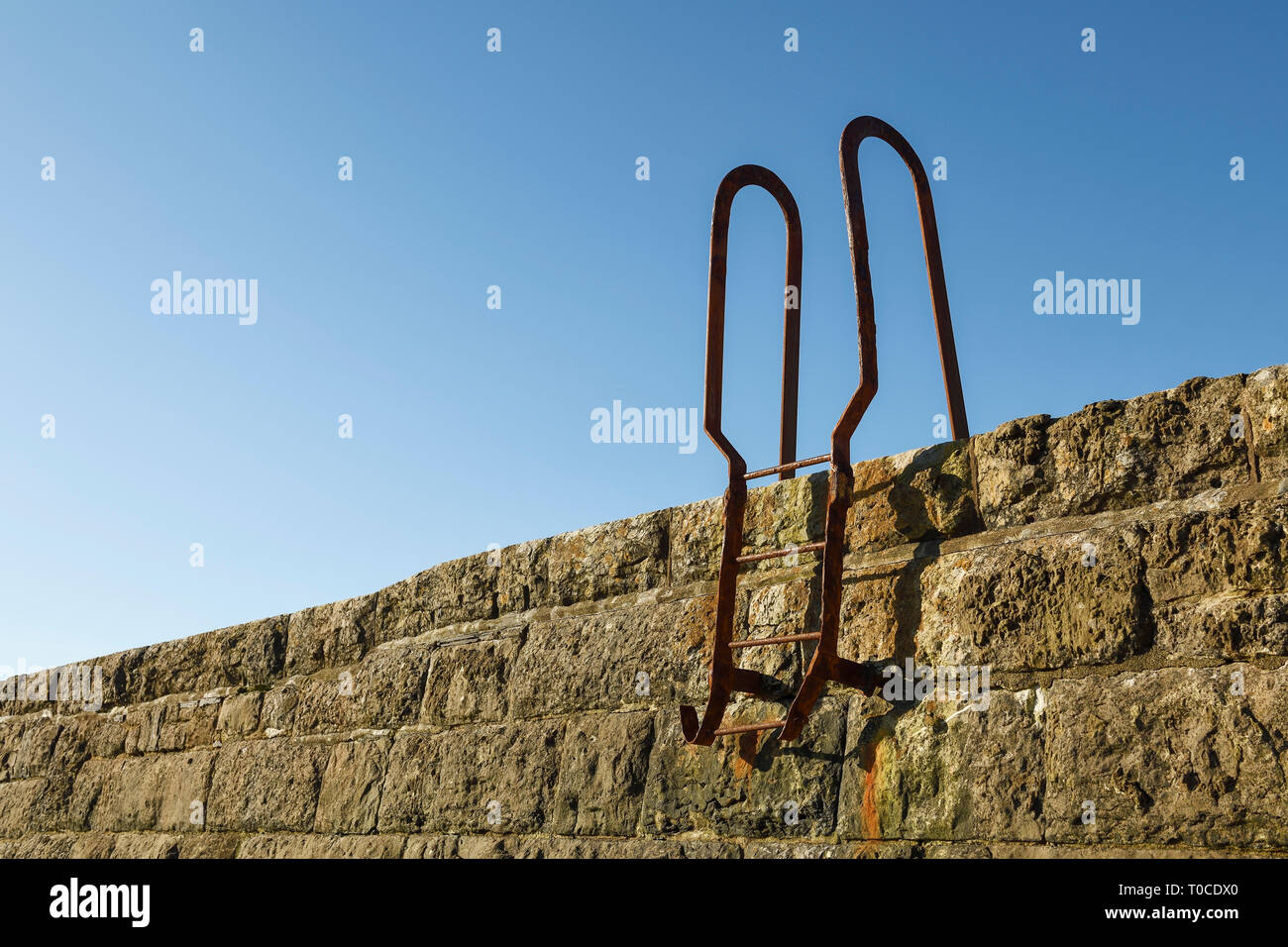 A rusting metal ladder on the sea wall at Beaumaris seafront, North ...
