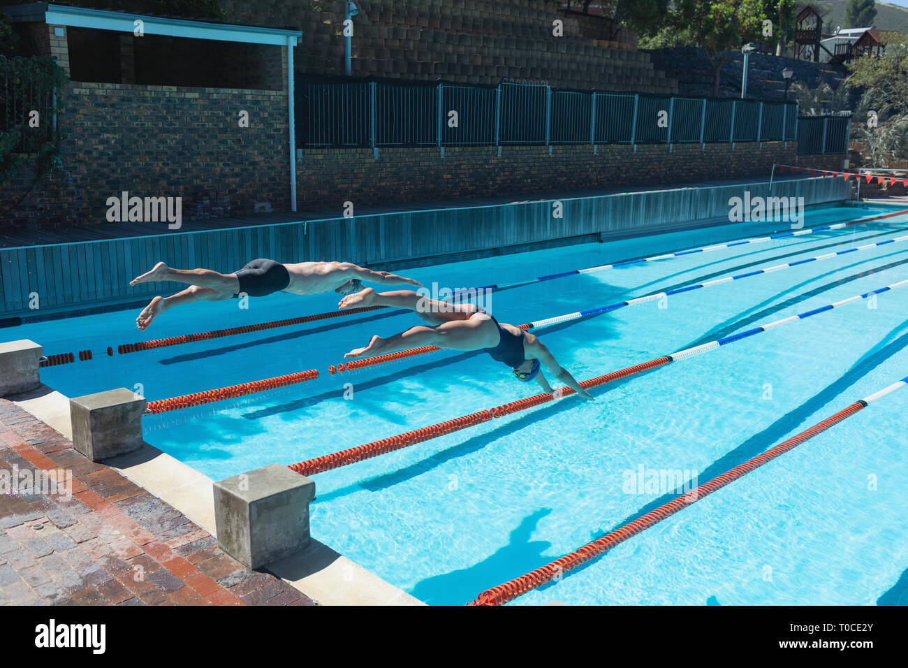Young swimmers jumping into water at swimming pool Stock Photo - Alamy