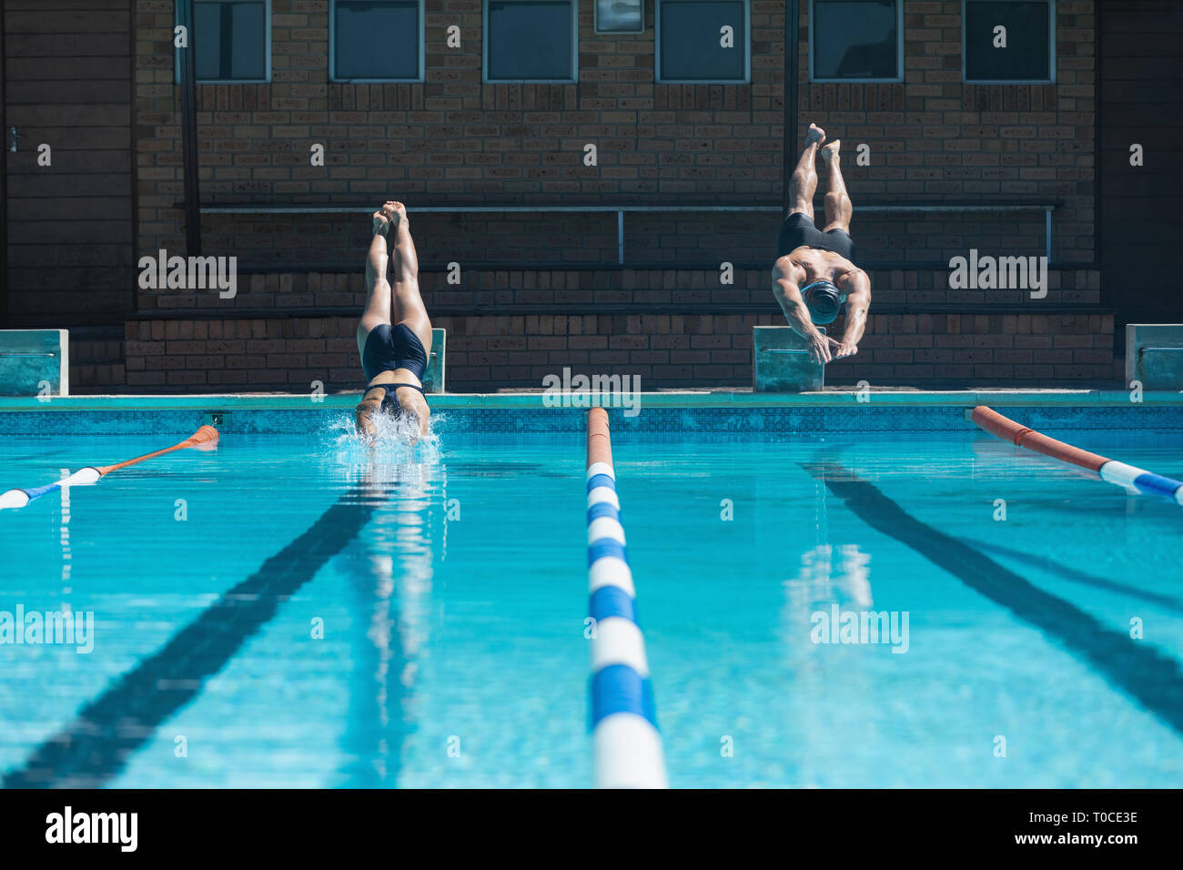 Young swimmers jumping into water at swimming pool Stock Photo - Alamy