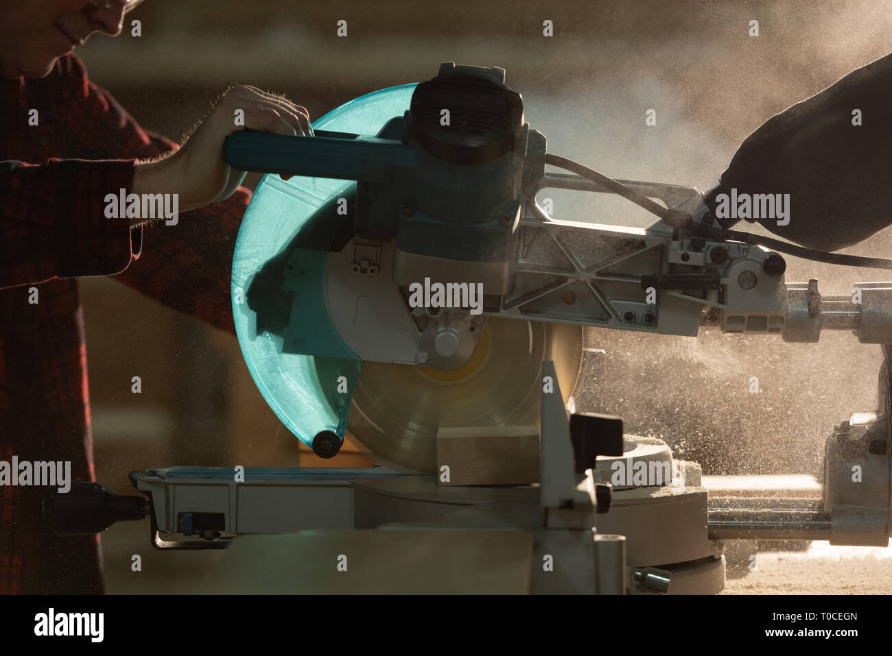 Carpenter cutting a piece of wood with a mechanic saw at workshop Stock ...