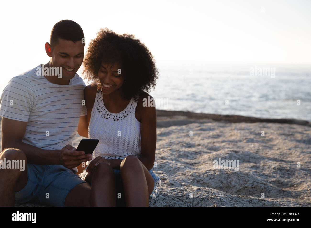 Couple using mobile phone at beach Stock Photo - Alamy