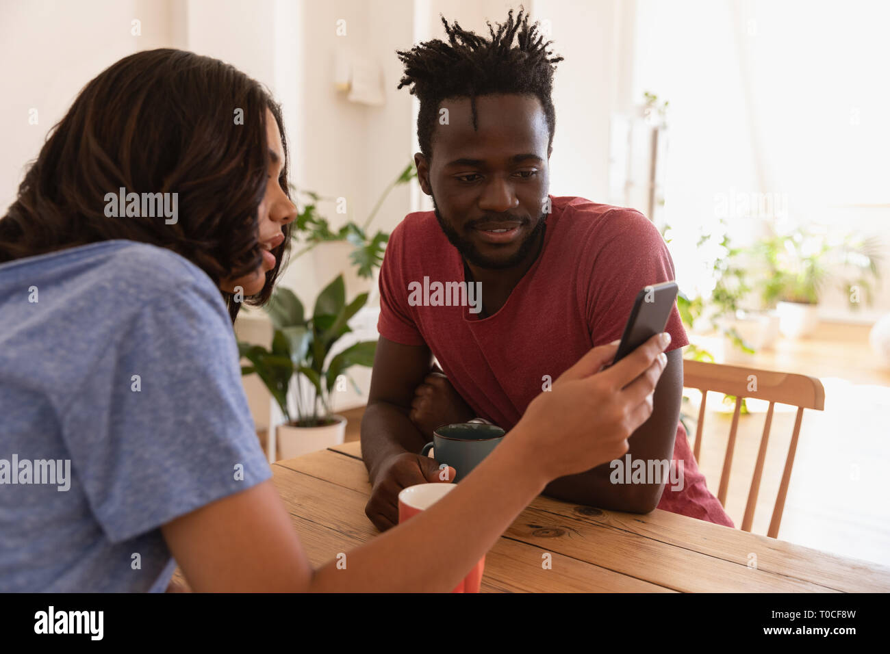 Couple using mobile phone at home Stock Photo - Alamy