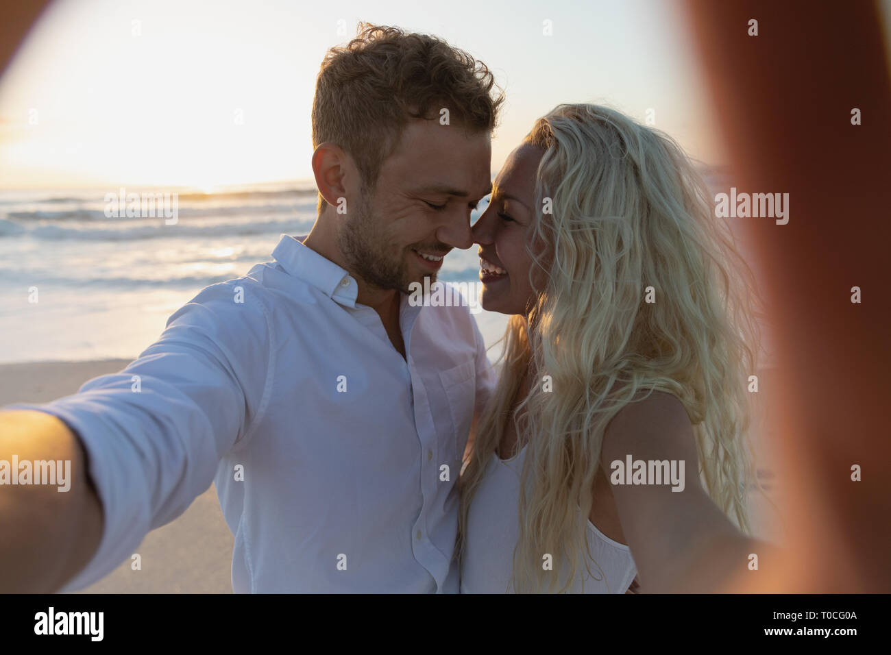 Caucasian love couple embarrassing each other while standing at beach ...