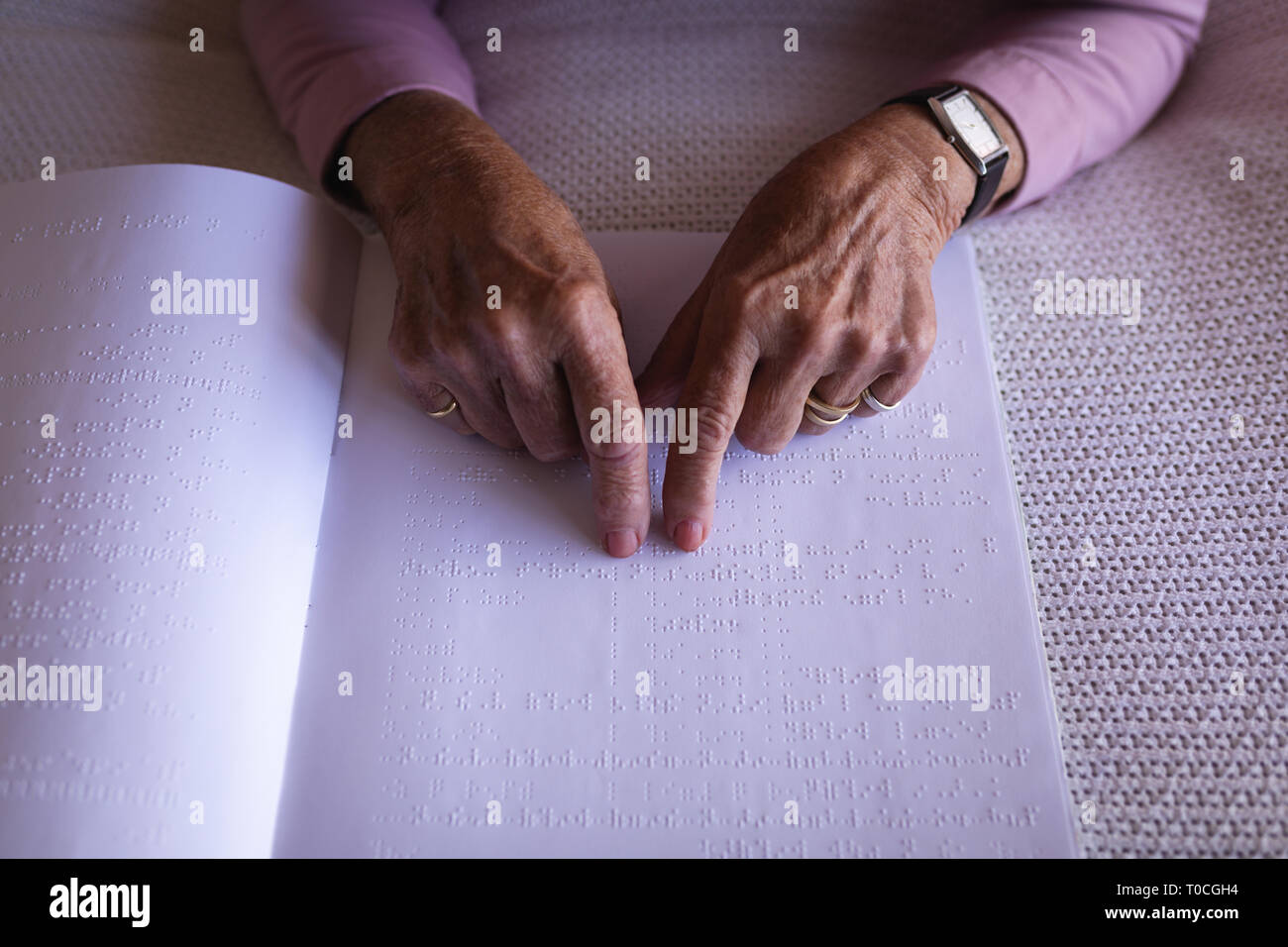 Blind active senior woman hands reading a braille book on bed in ...