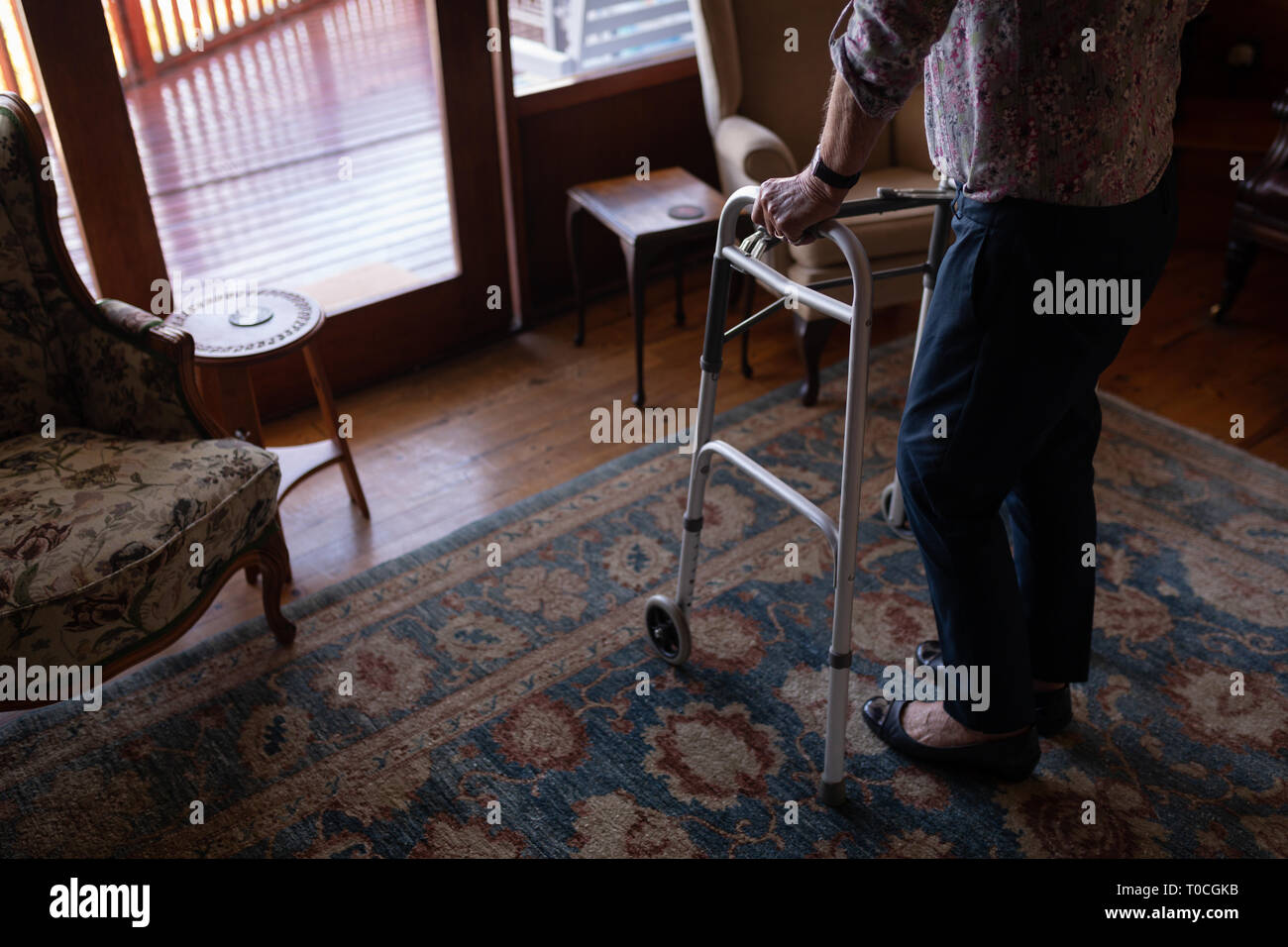 Active senior woman walking with walker in living room at home Stock ...