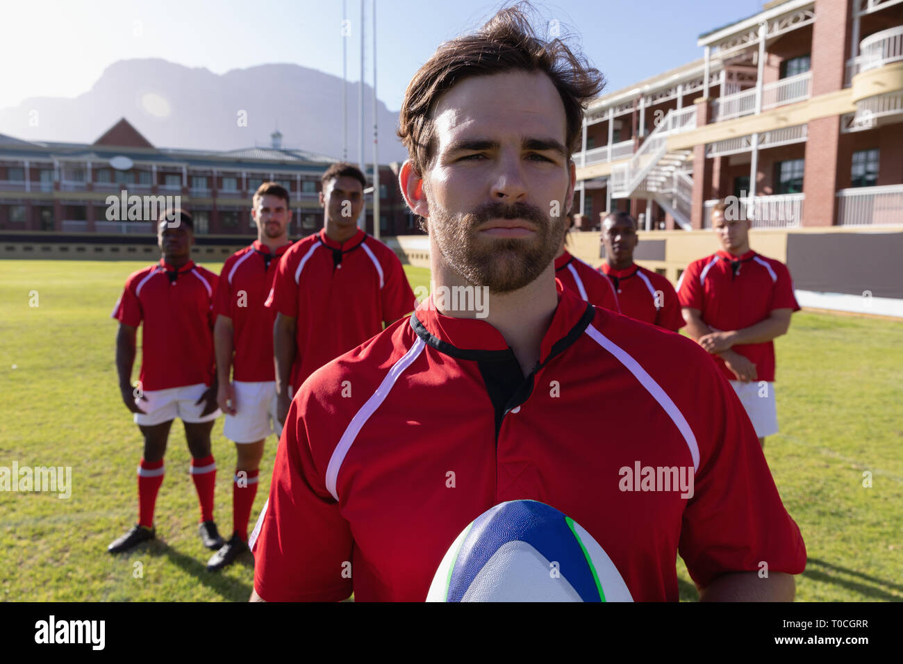 Team of male rugby players standing with rugby ball in the rugby ground ...