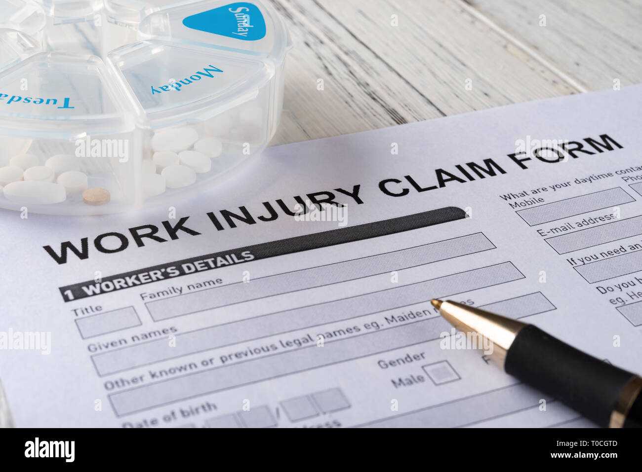 work injury claim form with box of pills and a pen medical and ...
