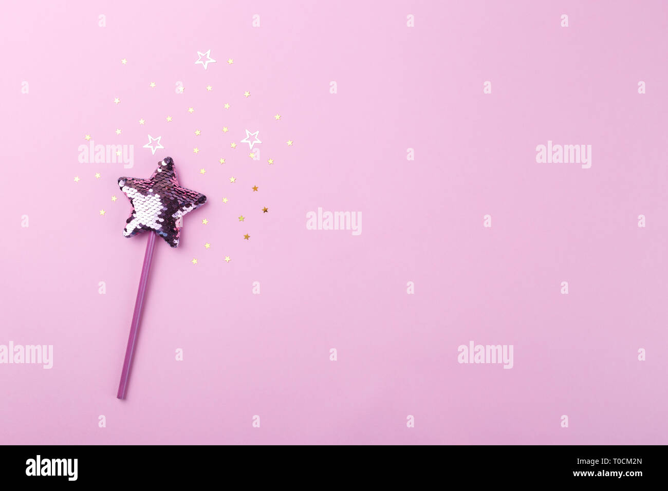 Sparkling magic wizard wand star shape on pink background, copy space ...