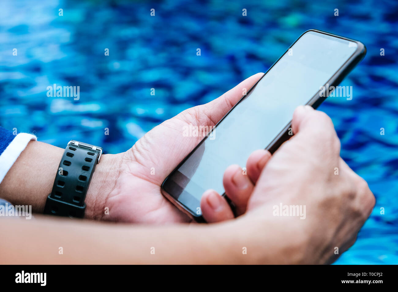 Man using smartphone by the pool Stock Photo - Alamy