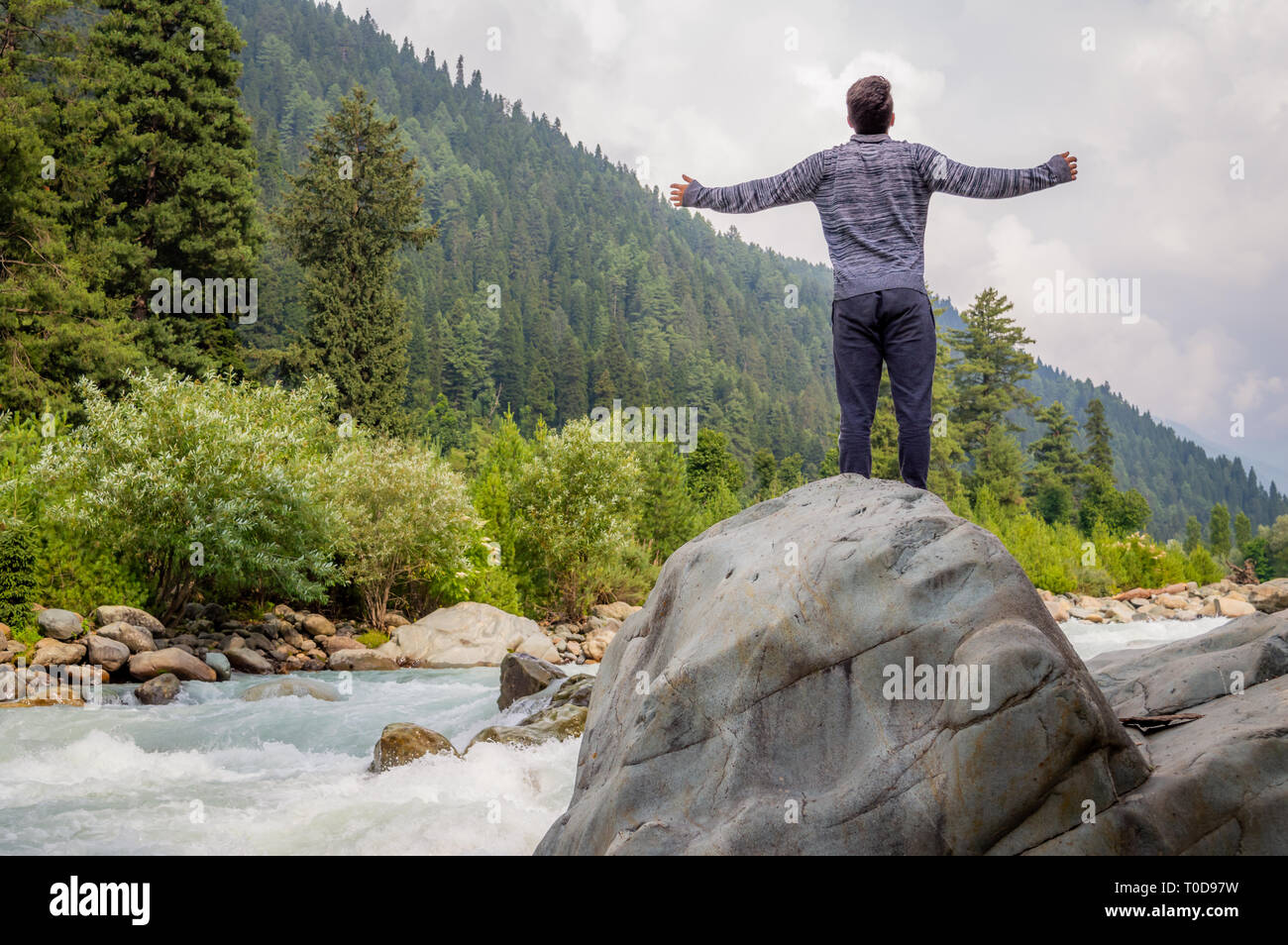 A person standing with his arms wide open in front of mountains in ...