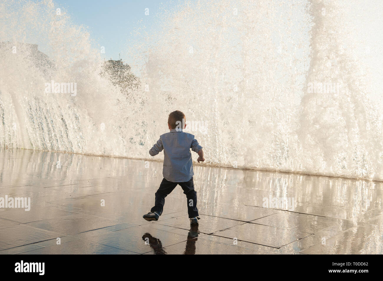 active small kid escaping from huge water wave in city Stock Photo - Alamy